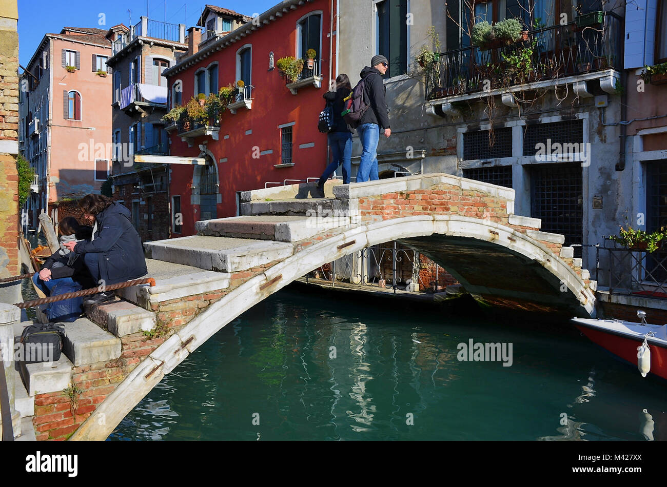 Venice, Italy. A couple of tourists crosses an ancient bridge without a ...