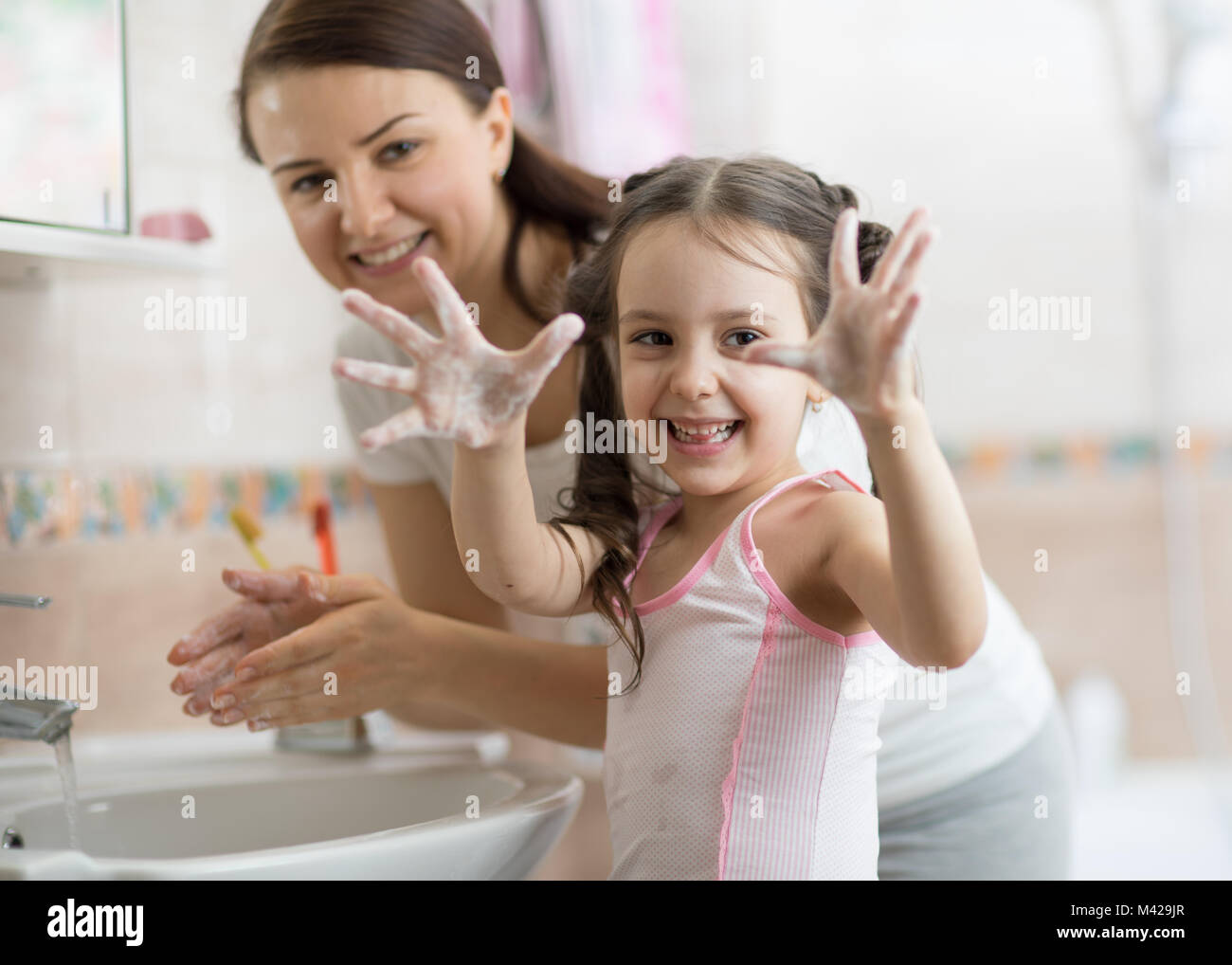 Pretty woman and child girl washing hands with soap in bathroom Stock ...