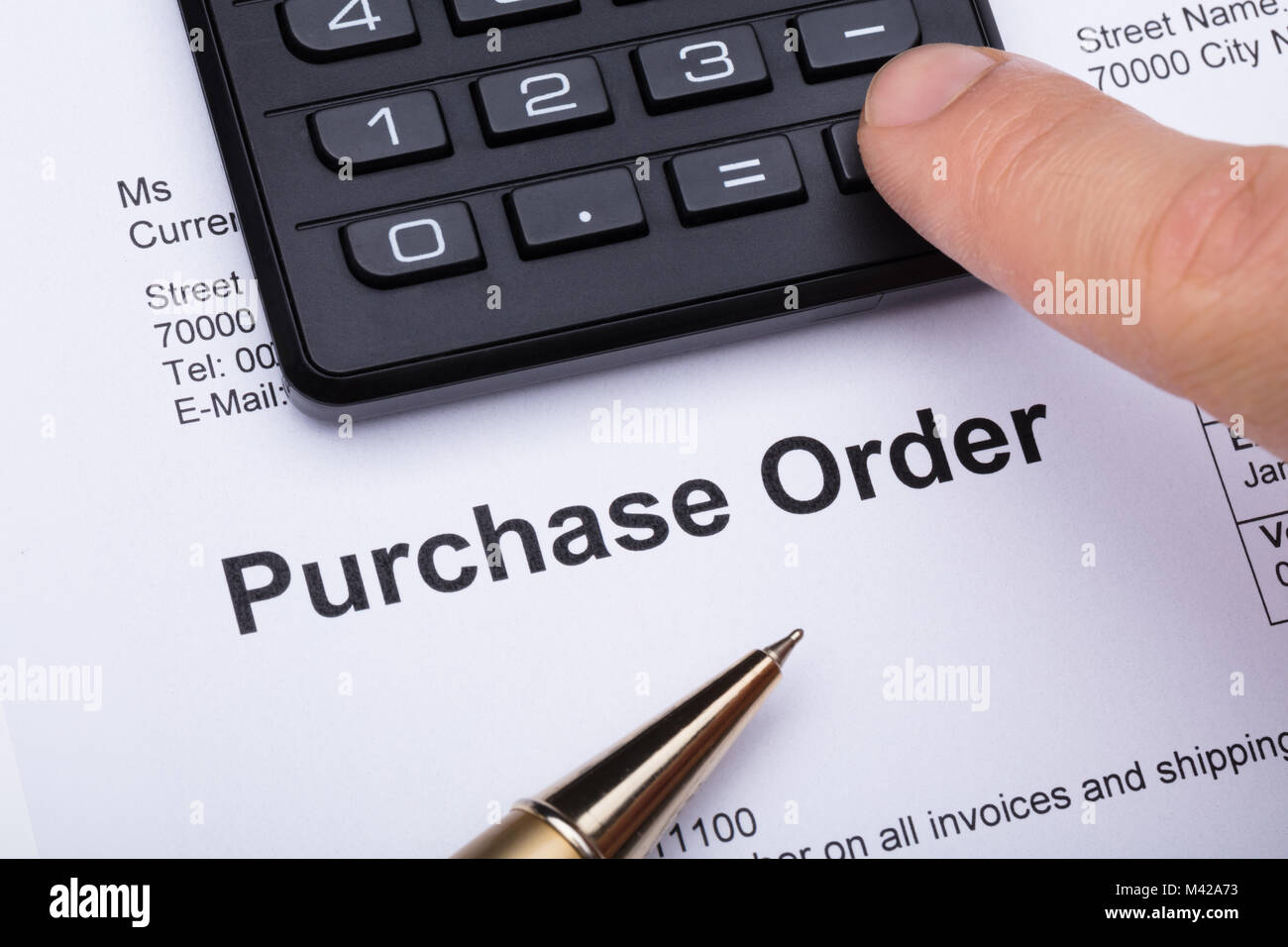 High Angle View Of Person Using Calculator On A Purchase Order Form And ...