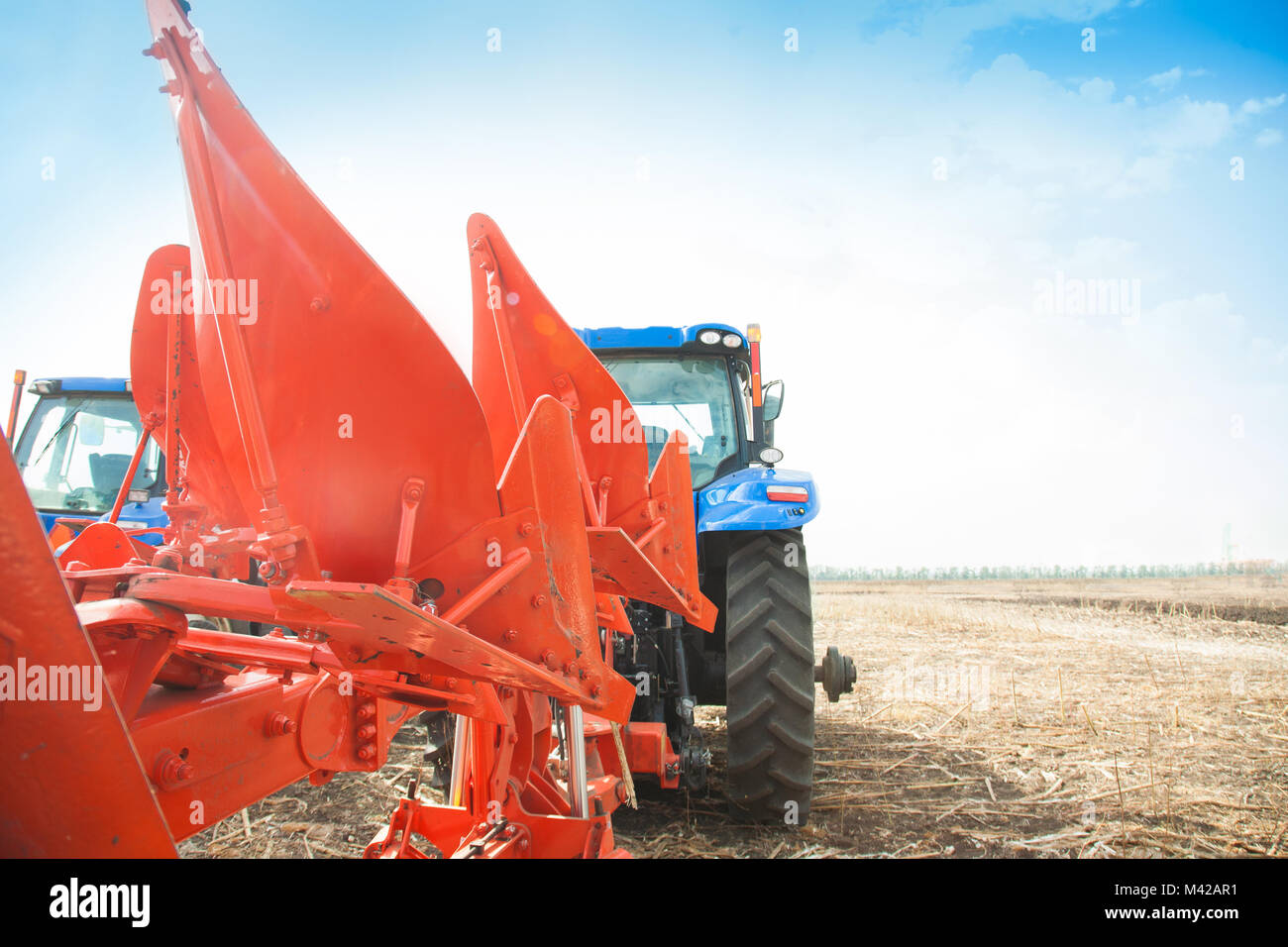 A modern tractor with a trailed plow on the field on a sunny day. The ...