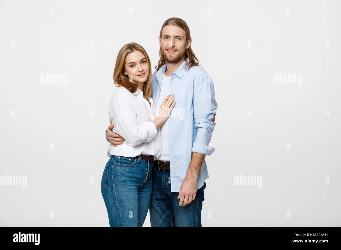 Portrait of cheerful young couple standing and hugging each other on ...