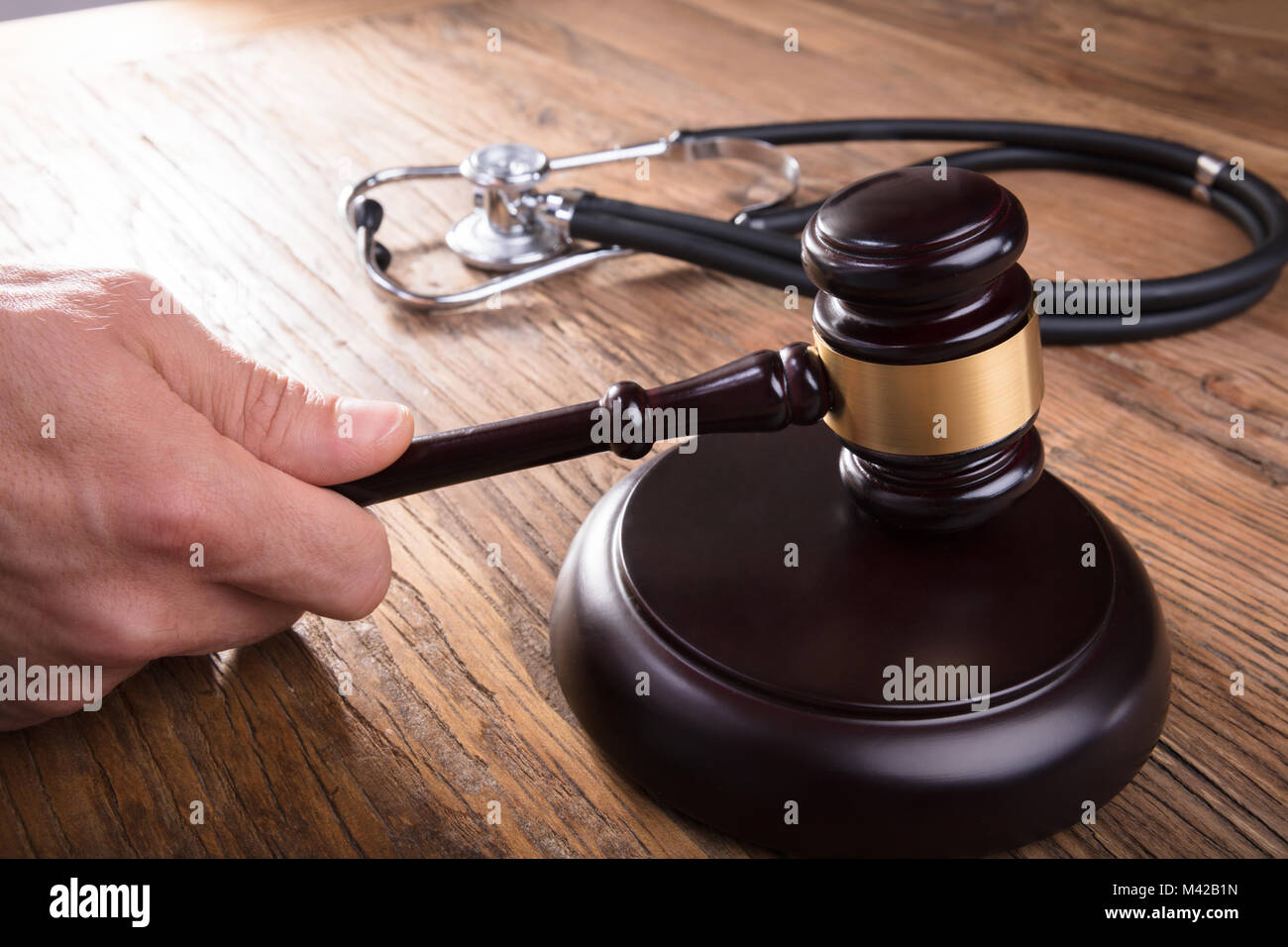 Close-up Of A Judge Hand Striking Gavel With Stethoscope On Wooden Desk ...