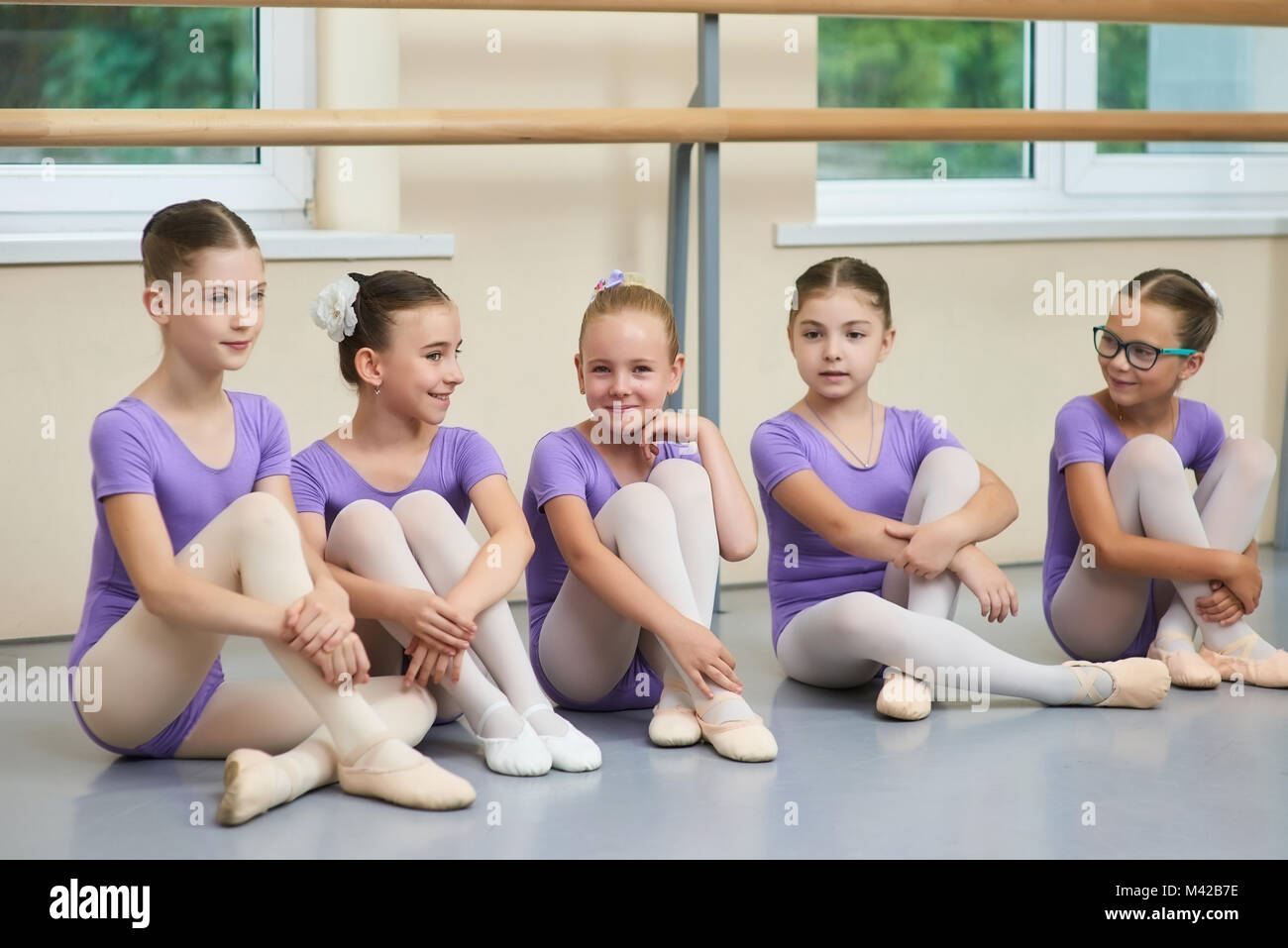 Young ballerinas sitting on the floor. Group of young cute ballet ...