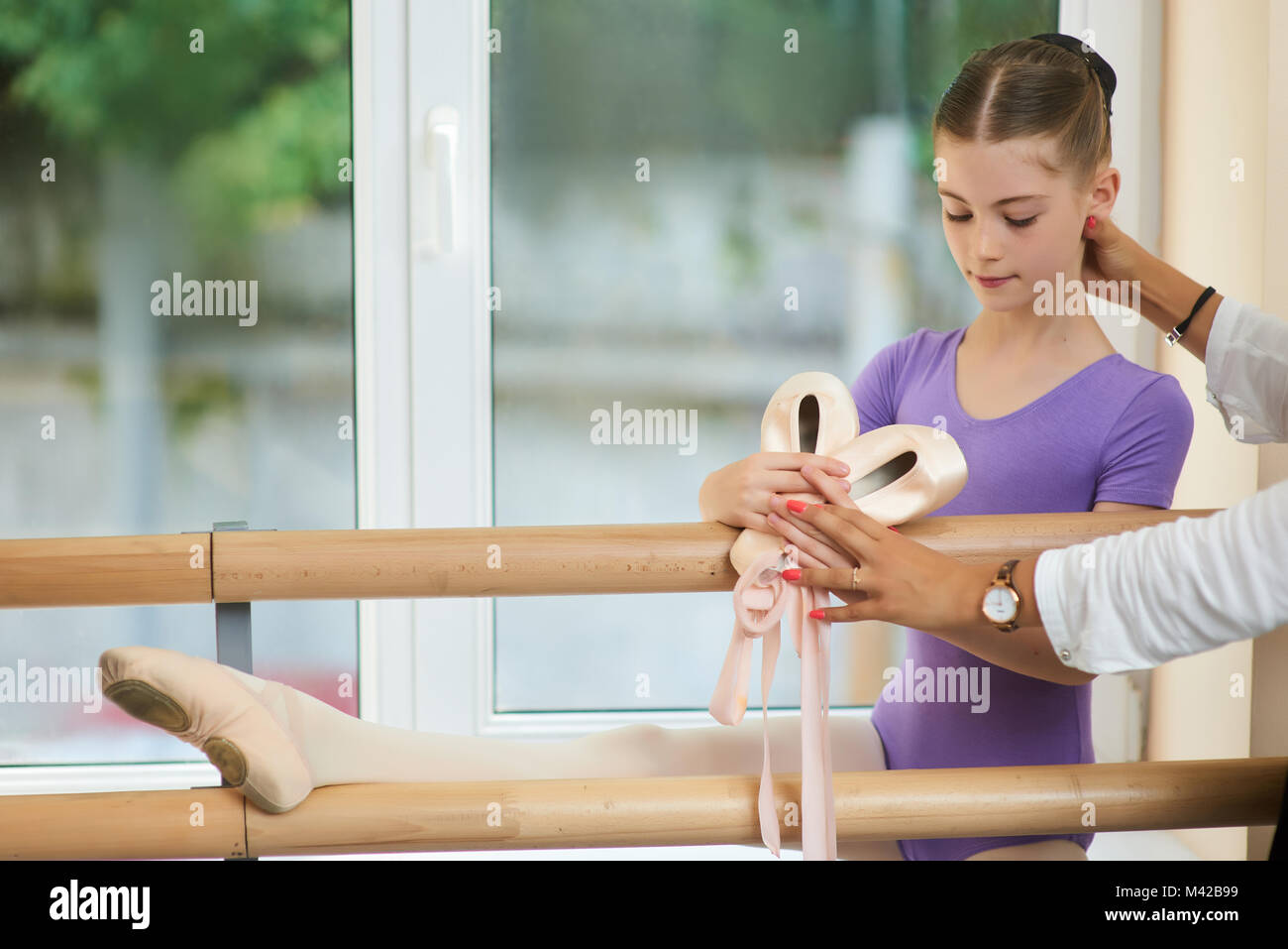 Little ballerina training stretch near barre. The ballet dance teacher ...