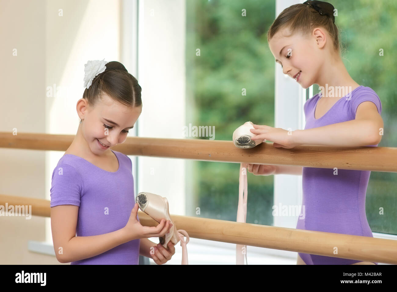Happy little ballerinas holding ballet shoes. Two beautiful friends at ...