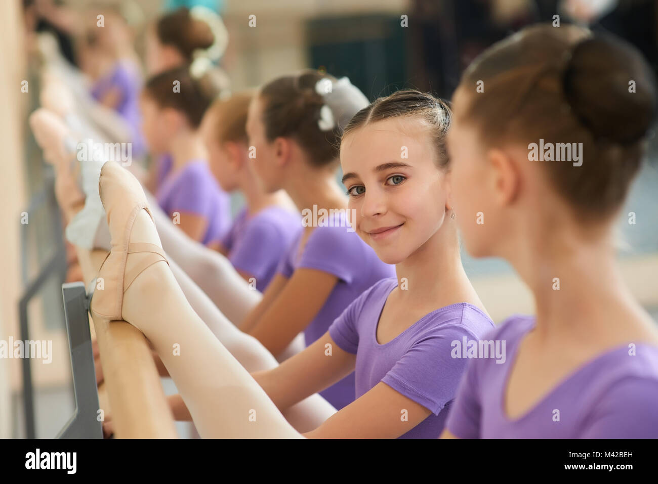 Beautiful smiling ballerina stretching leg. Young lovely ballerina ...