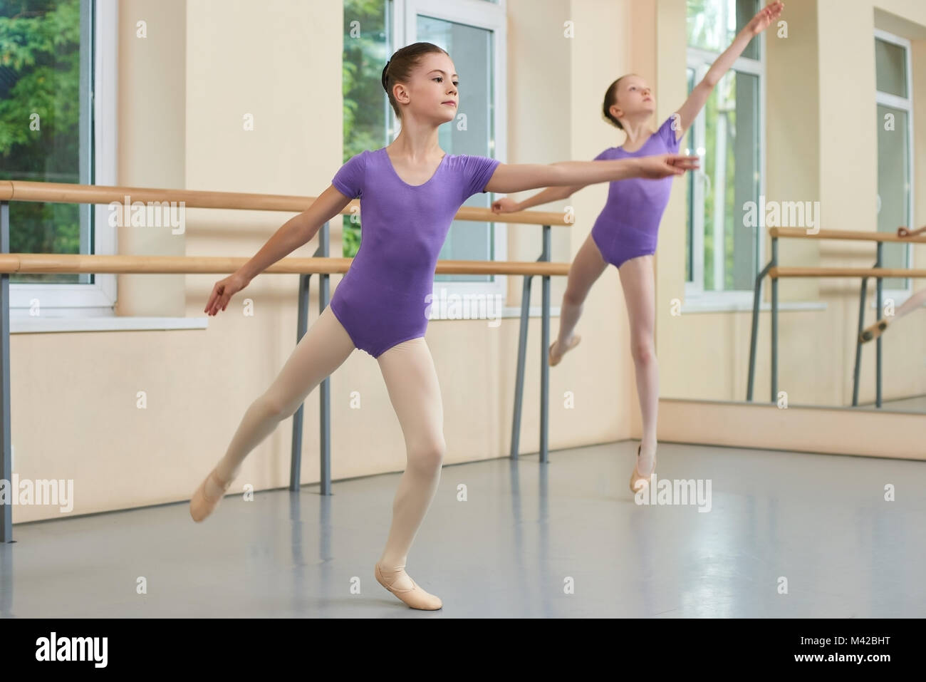 Cute ballet girl dancing in studio. Two young ballerinas performing ...