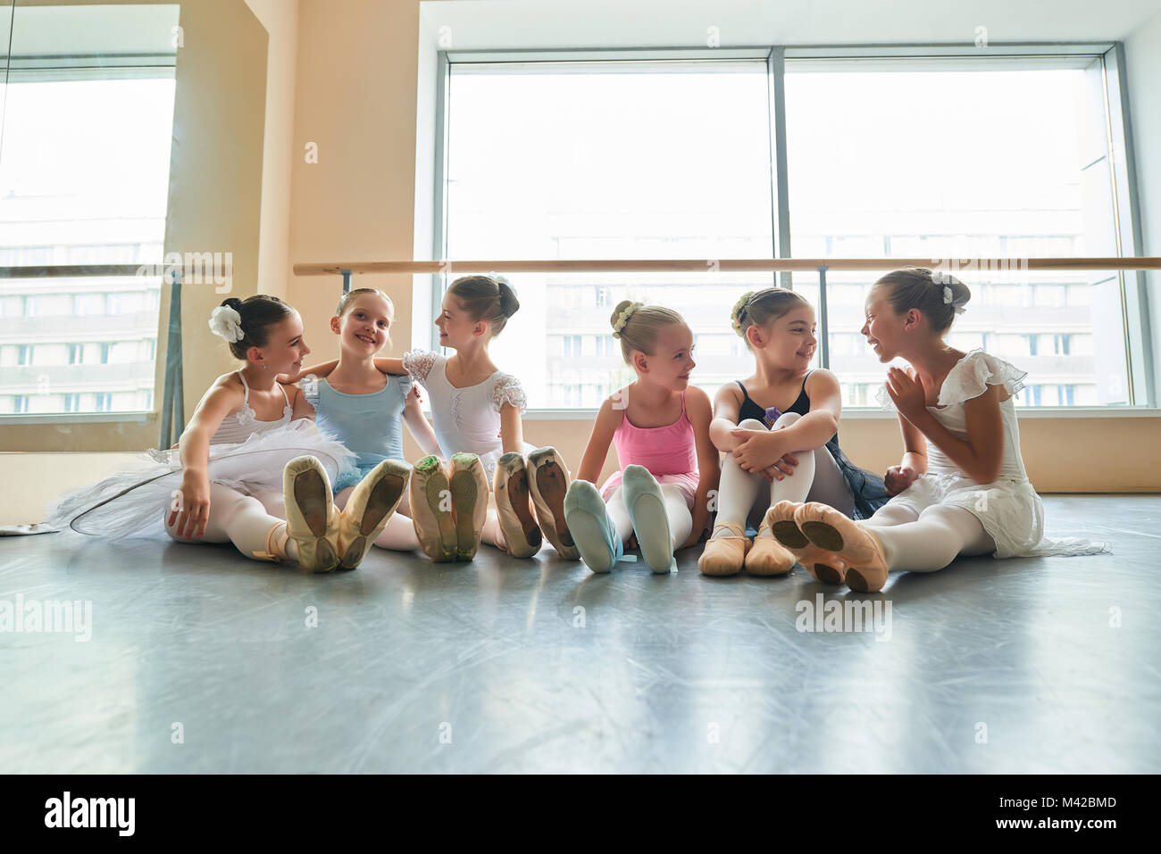 Young ballerinas sitting on floor and embracing. Cute little girls ...
