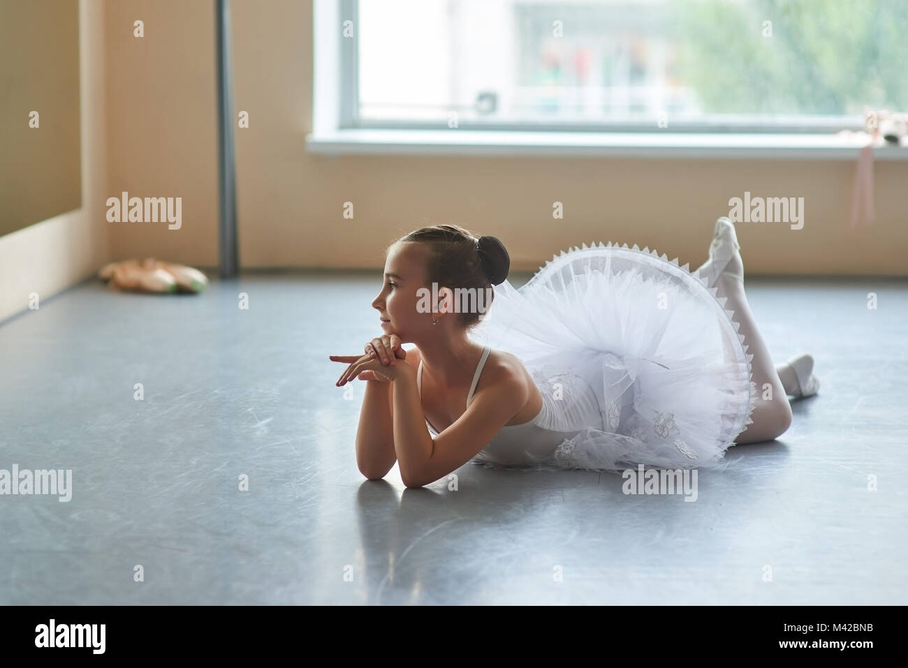 Adorable ballerina lying on the floor. Beautiful young ballet girl in ...