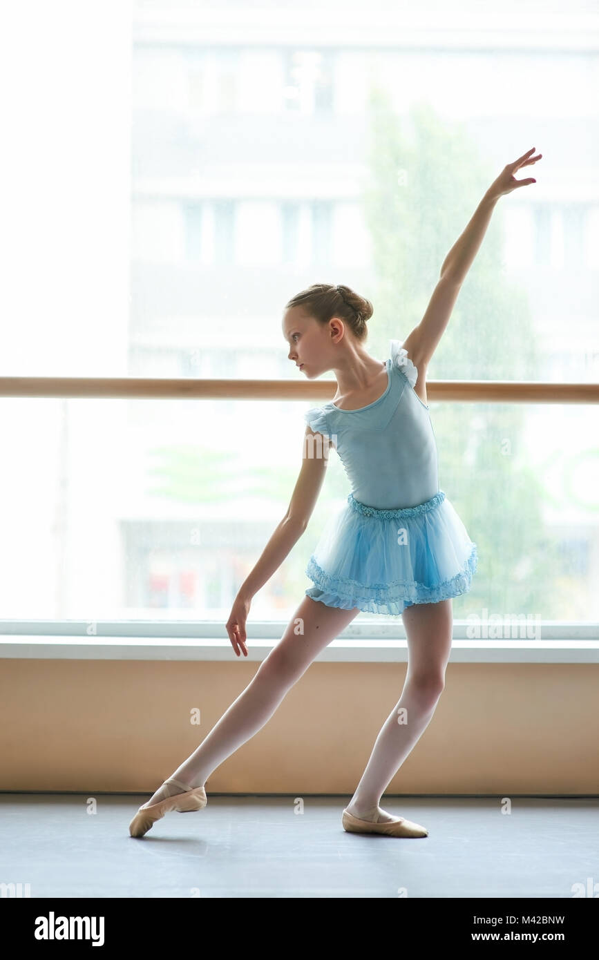 Young ballerina in blue dress practicing in studio. Cute ballet girl ...