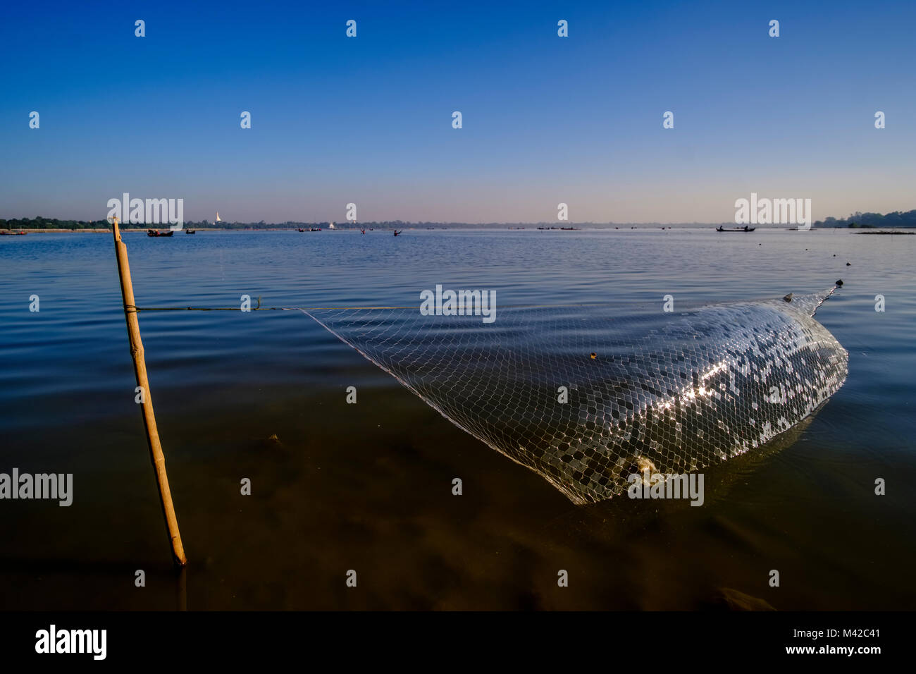 A fishing net, spanned in the shallow water of Taungthaman Lake, is ...