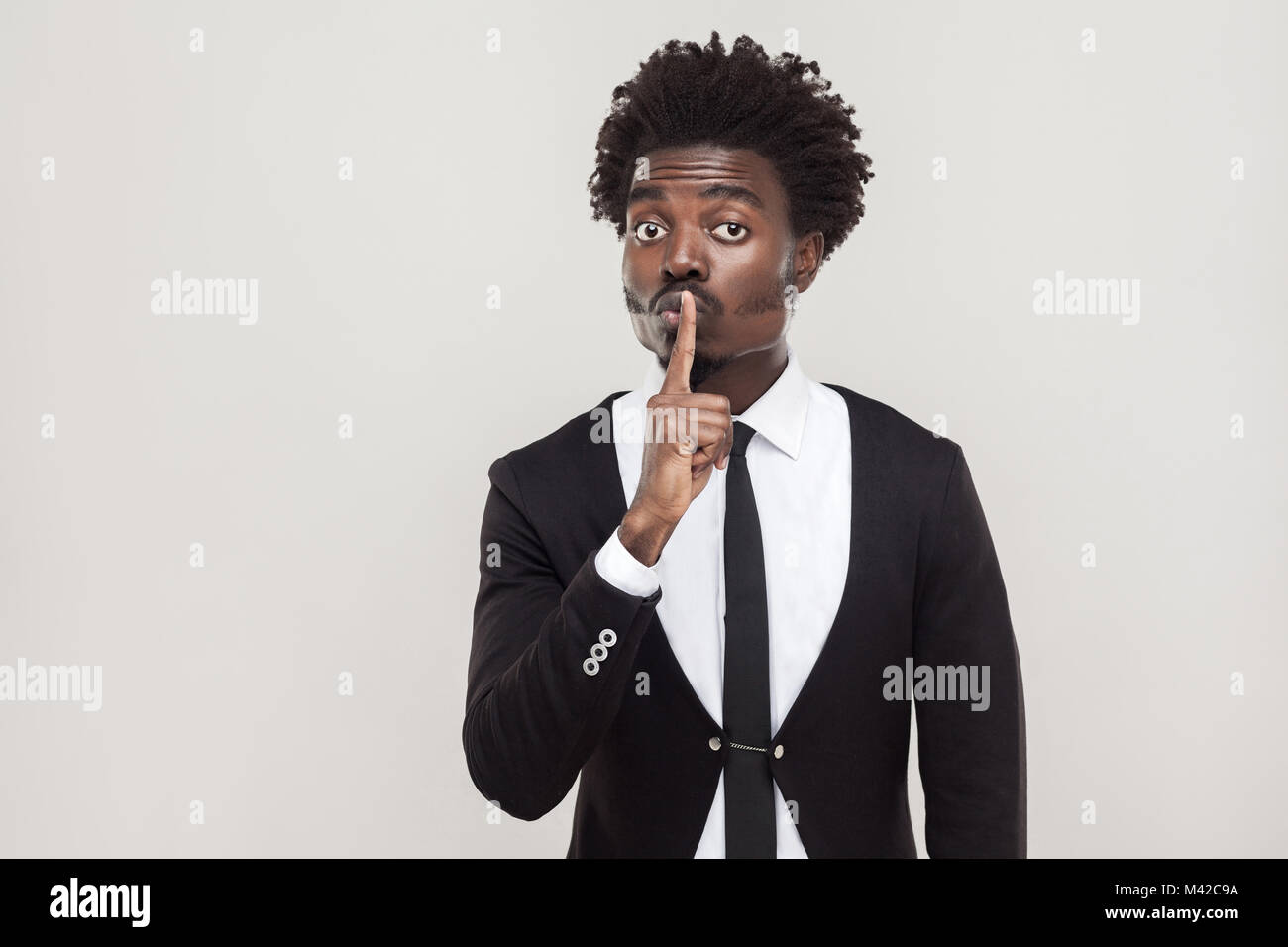 Secret or quiet concept. African businessman showing shh sign at camera ...