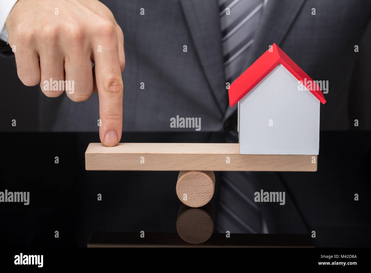 Close-up Of A Person's Finger Balancing House Model On Wooden Seesaw ...