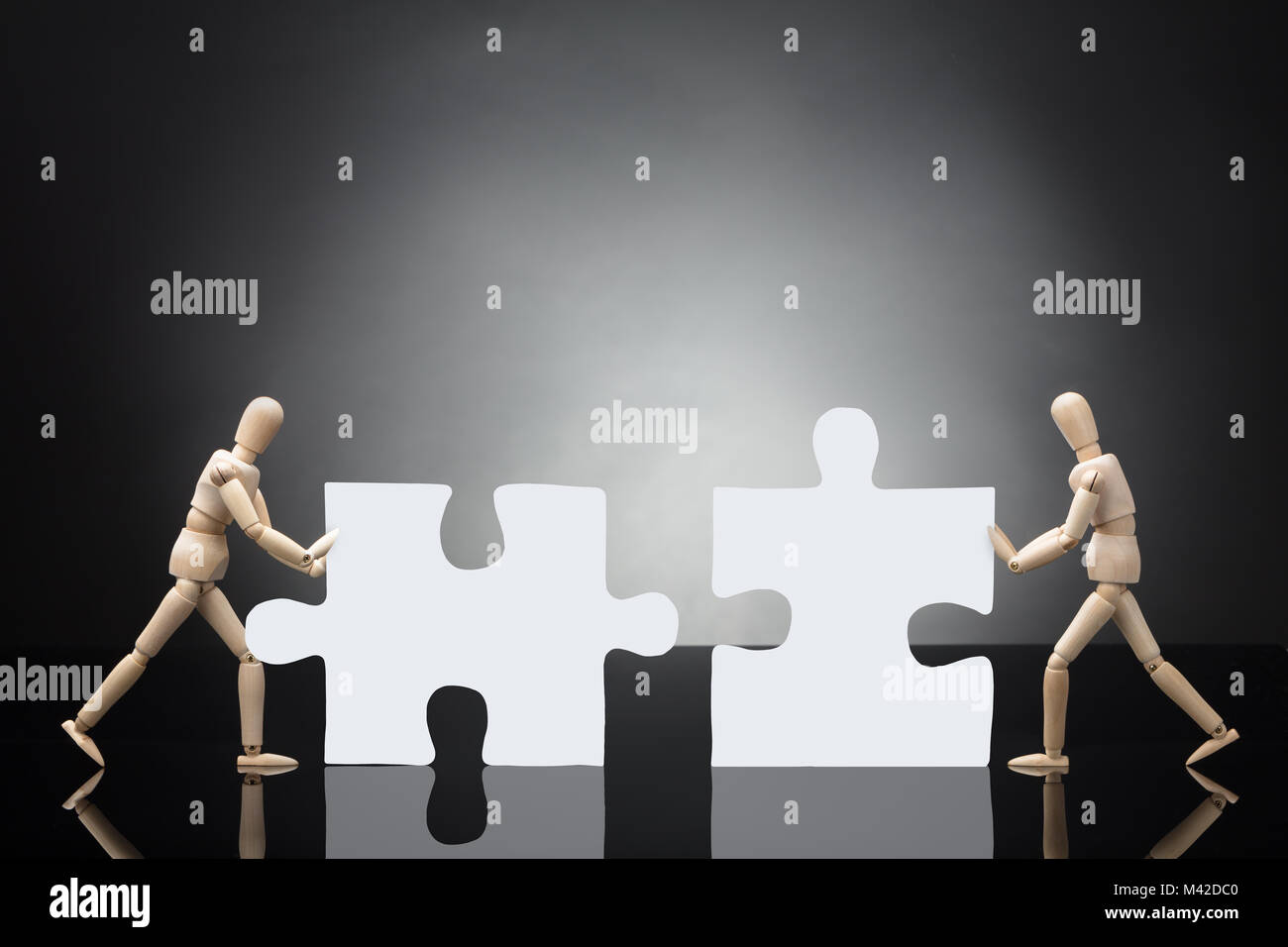 Two Wooden Dummies Solving White Jigsaw Puzzle On Grey Background Stock ...