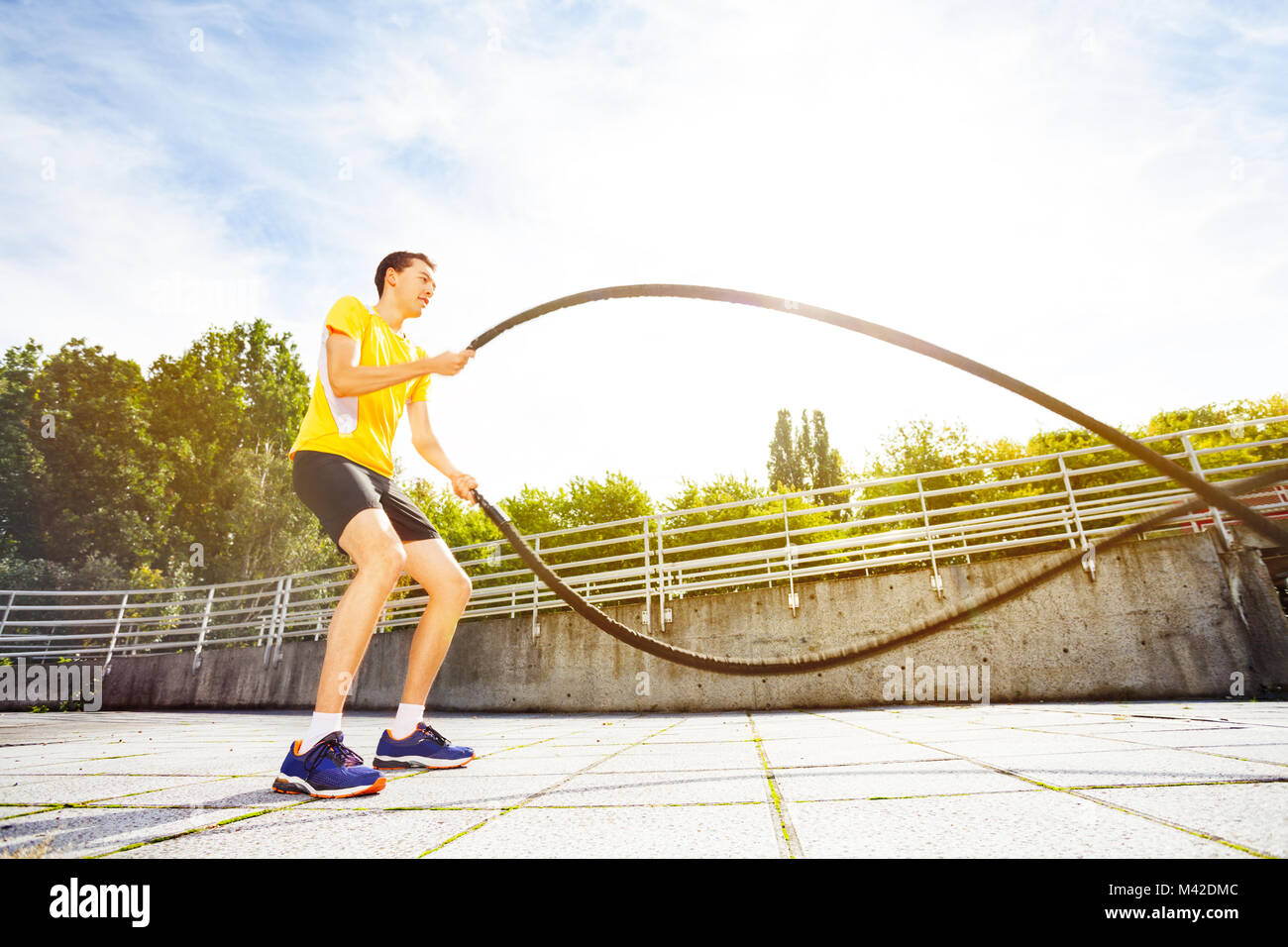 Athlete making wave movement with muscle rope during crossfit workout ...