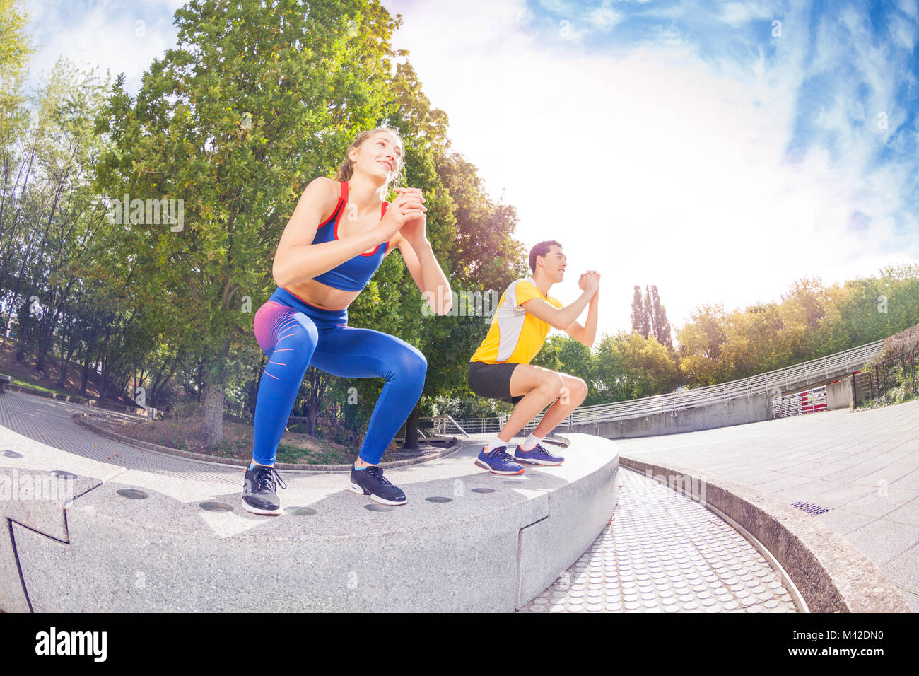 Fit young couple jumping on border during crossfit workout at city park ...