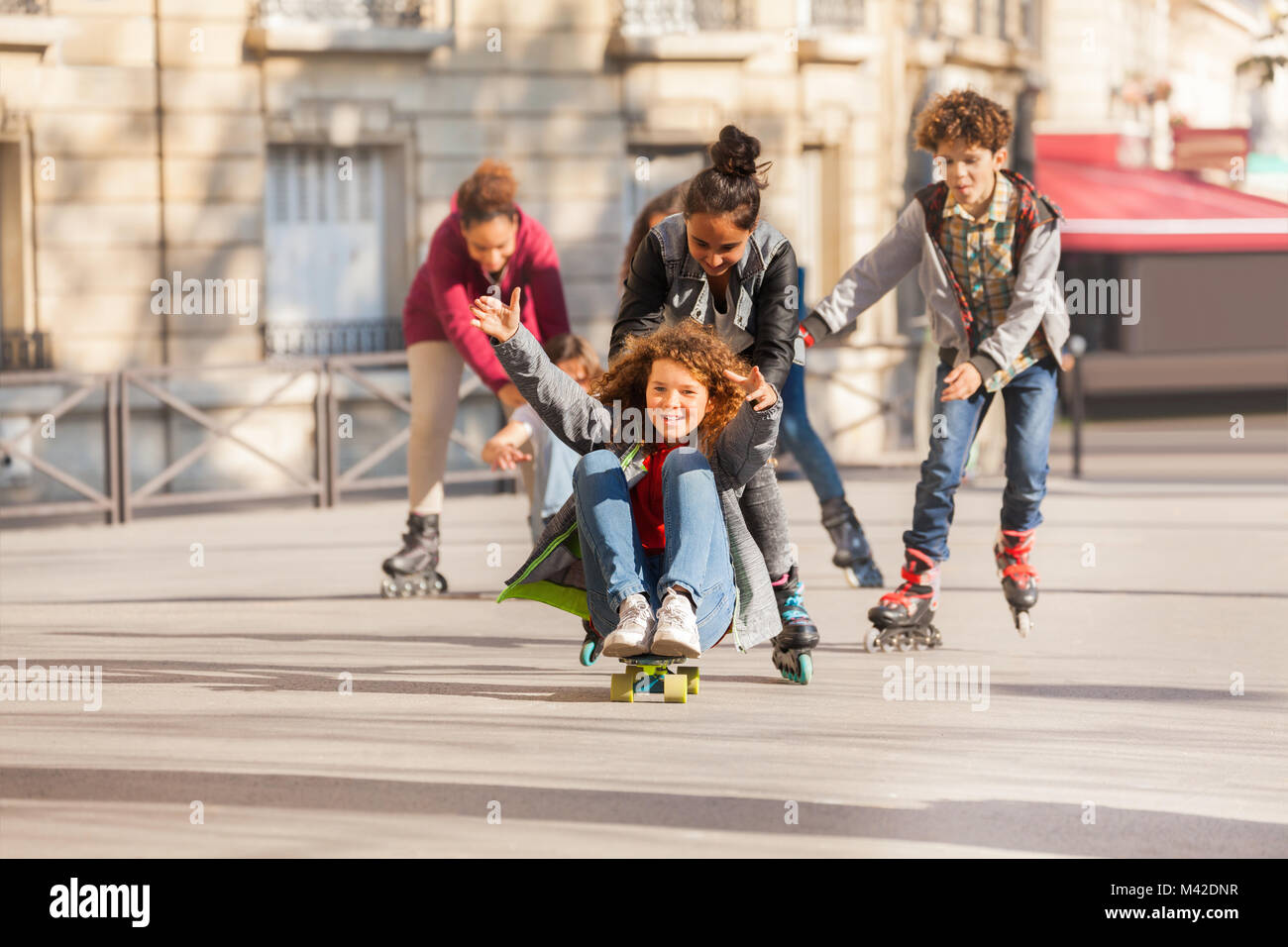 Happy teenagers having fun rollerblading and skateboarding during ...