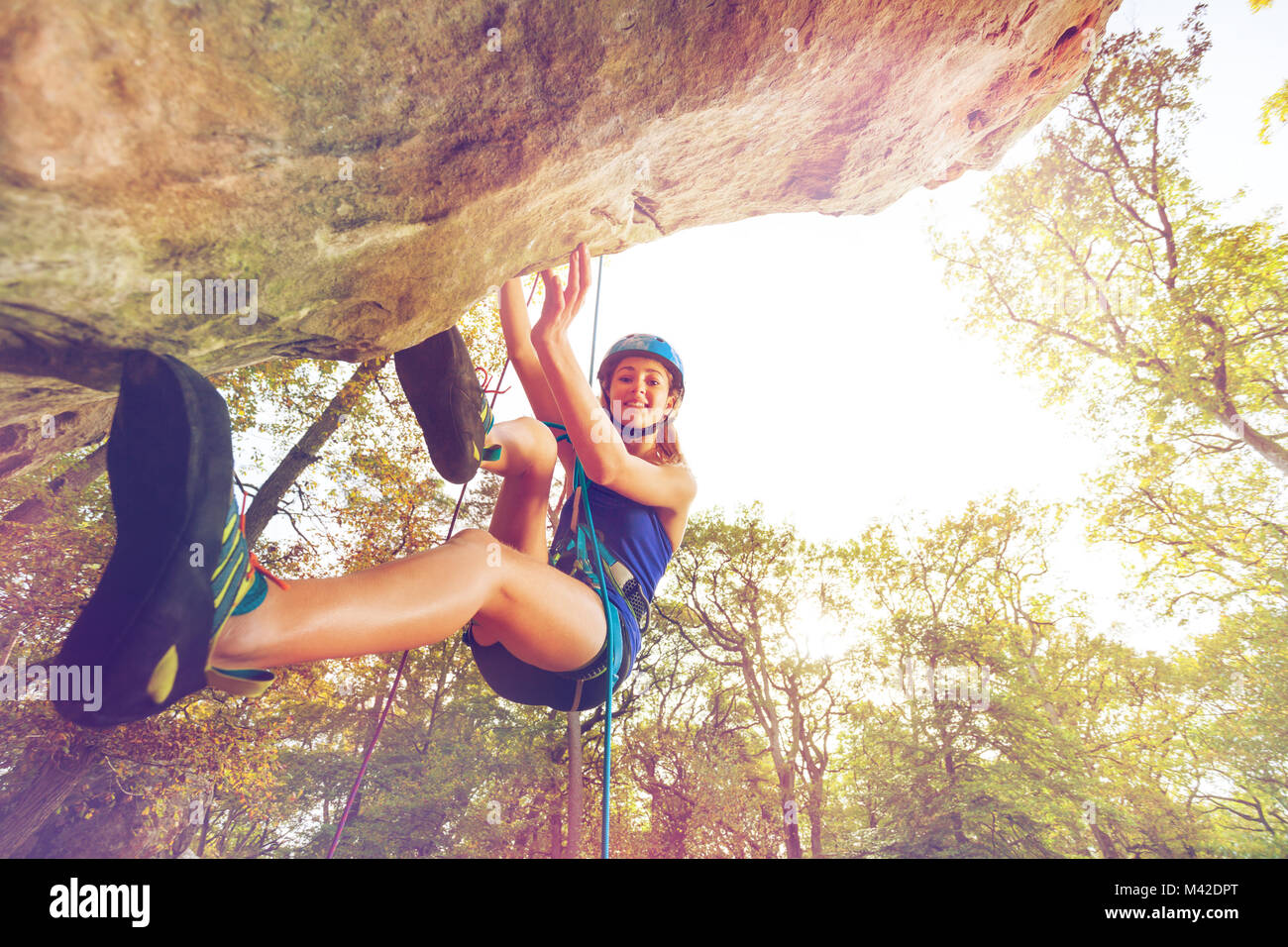 Low angle view of female rock climber training outdoors at sunny day ...