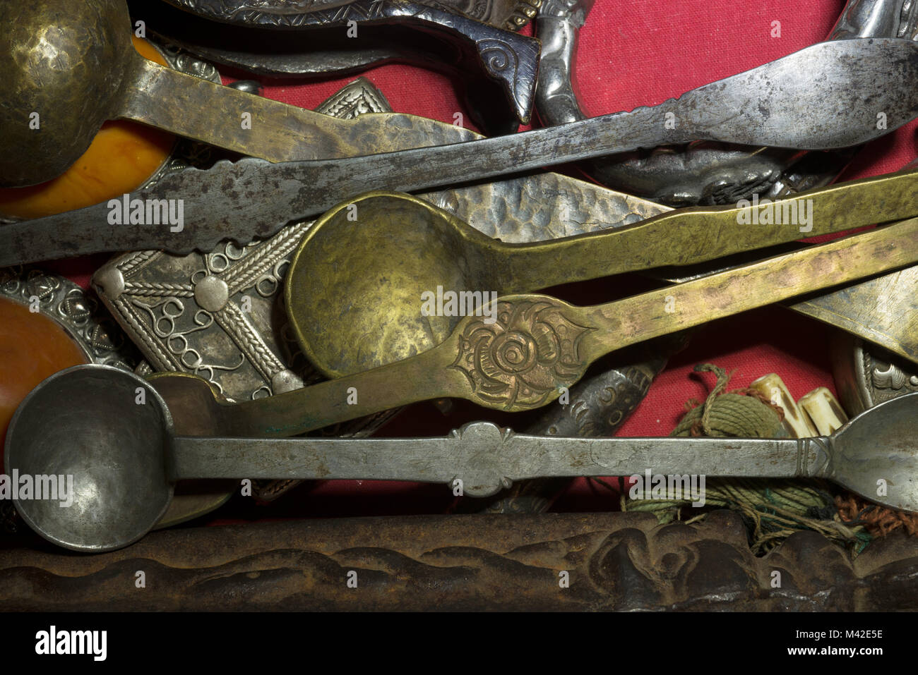 Antiquarian copper ancient spoons yellow and gray on red background ...