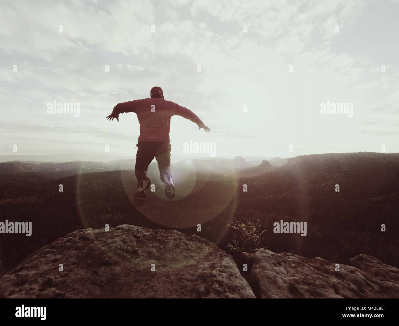 Man jumping from the mountain edge. Man jumping off a cliff without ...