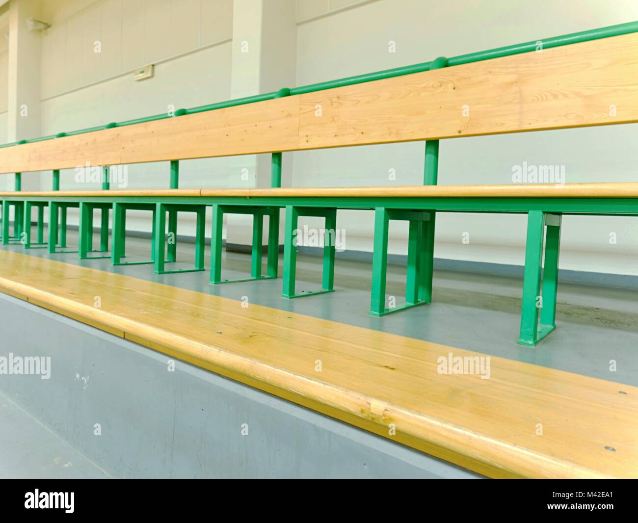 Rows of empty wooden benches in school sporting hall. Tribune in gym ...