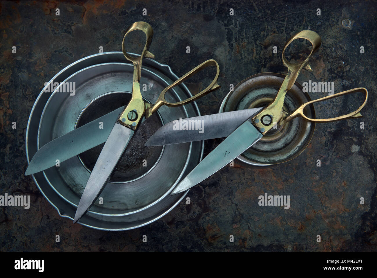 Two old scissors lie on silver circles, diagonally along the frame, a ...