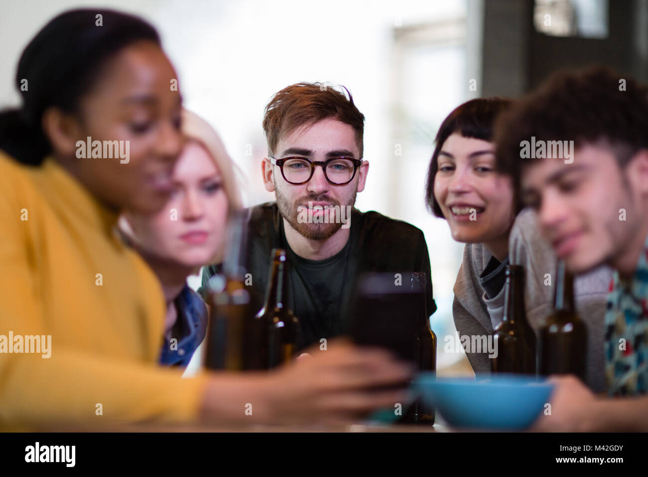 Group of friends looking at a smartphone together in a pub Stock Photo ...