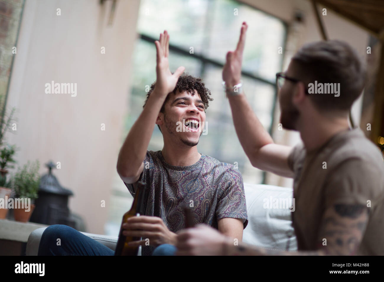 Two male friends giving high five Stock Photo - Alamy