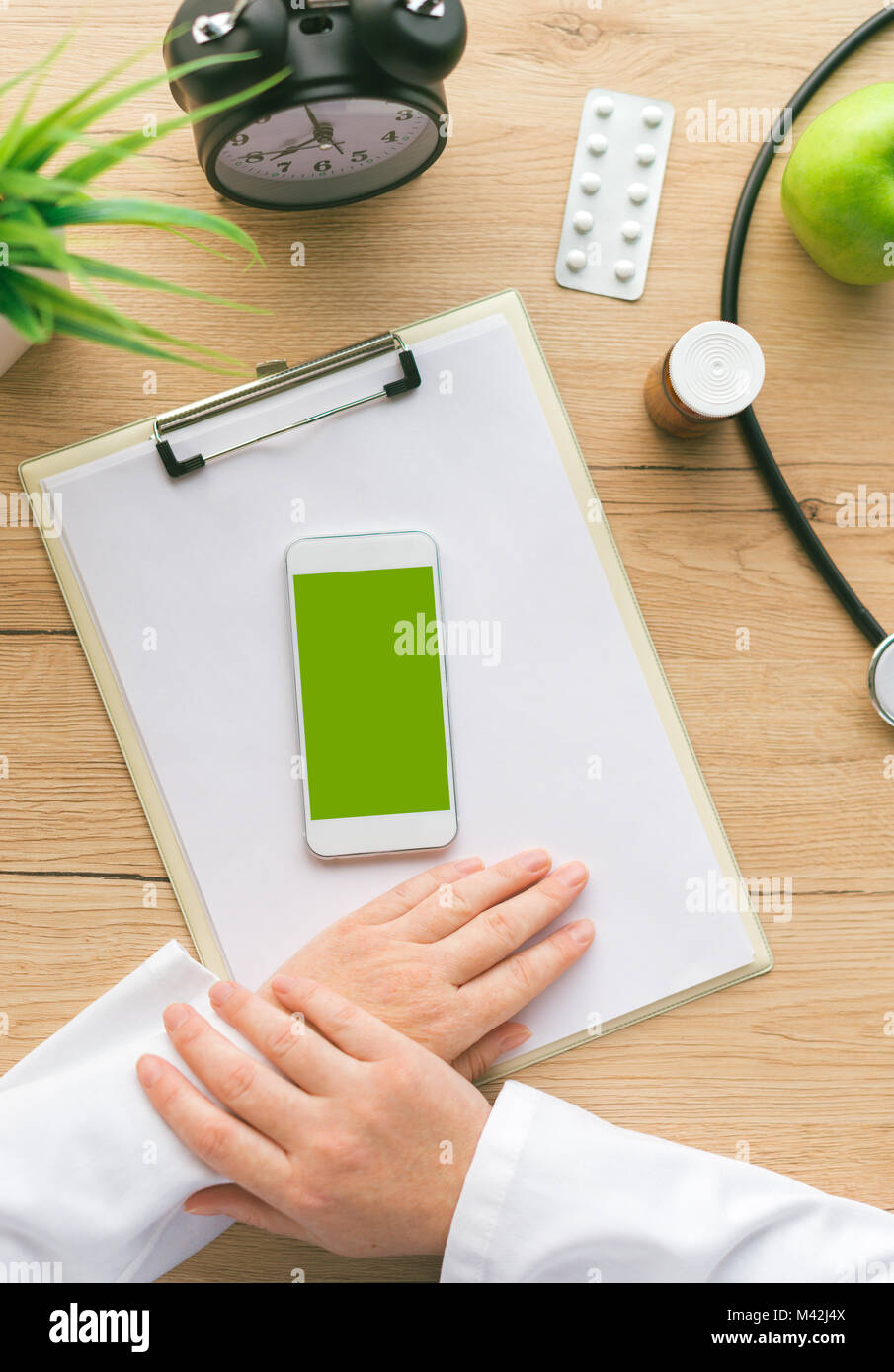 Doctor using smartphone app in hospital office, overhead view of female ...