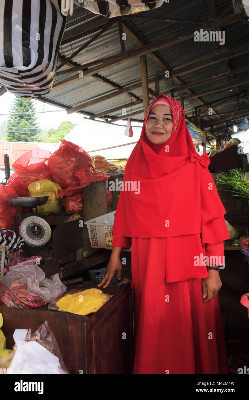 A vegetable and spice vendor in red hijab in Candi Kuning Market ...