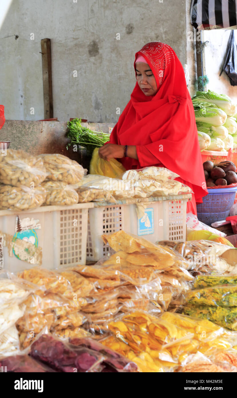 A vegetable and spice vendor in red hijab in Candi Kuning Market ...