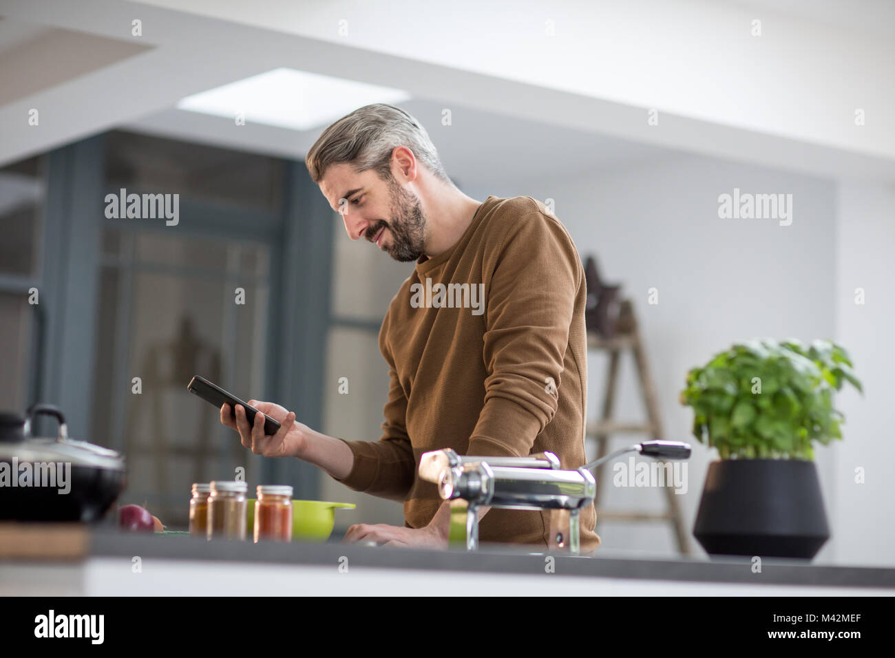 Adult male looking up recipe on smartphone in kitchen Stock Photo - Alamy