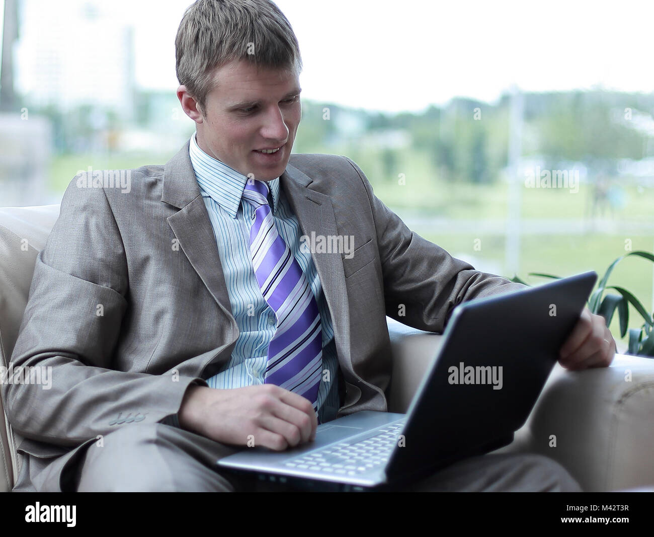 Young businessman sitting at office lobby working with laptop Stock ...