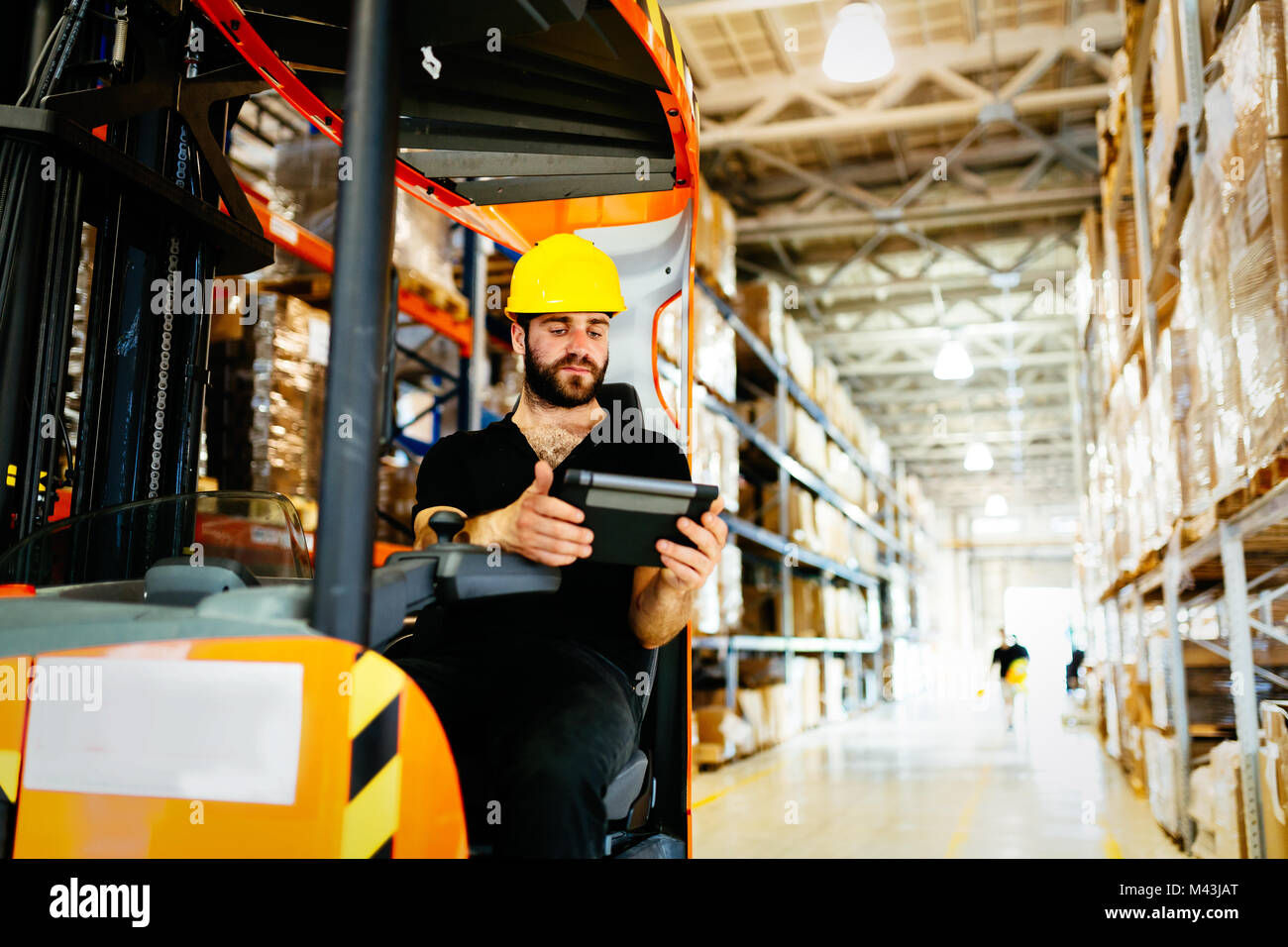 Warehouse worker doing logistics work with forklift loader Stock Photo ...