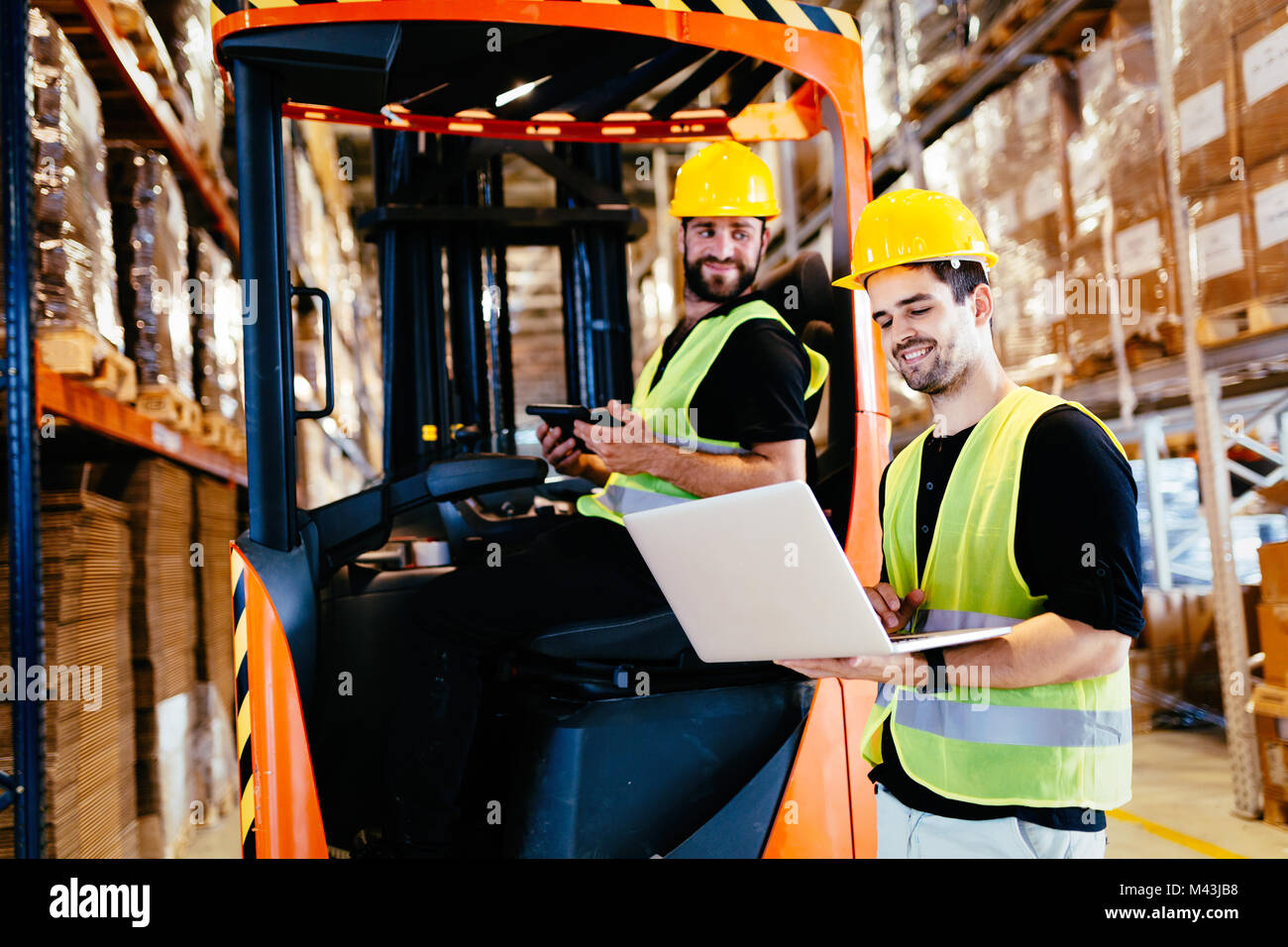 Warehouse workers working together with forklift loader Stock Photo - Alamy