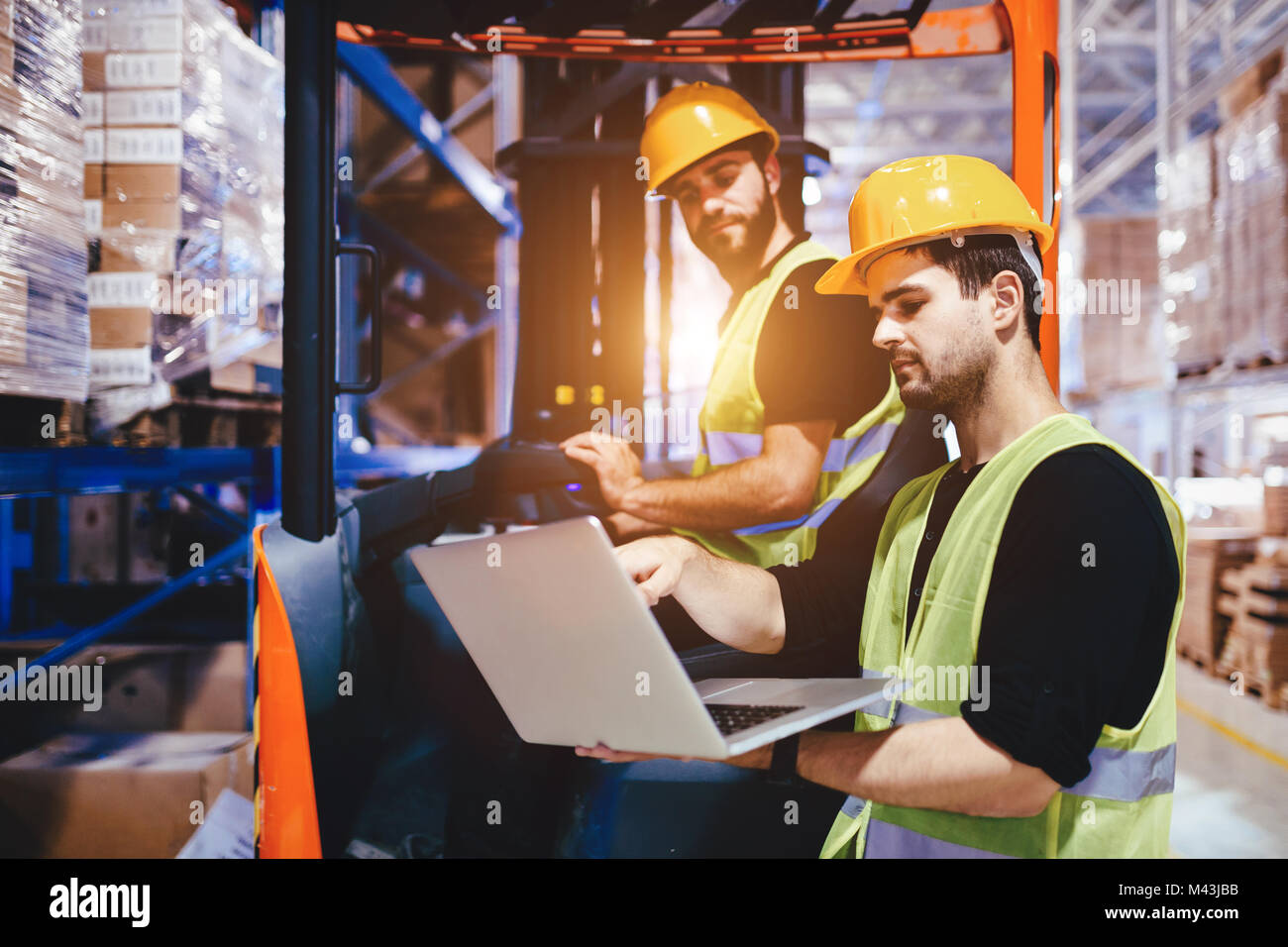 Warehouse workers working together with forklift loader Stock Photo - Alamy