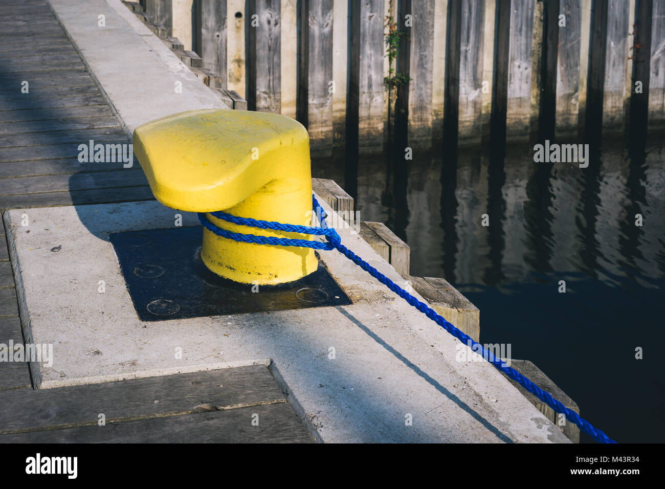 Yellow mooring bollard on pier with mooring rope Stock Photo - Alamy