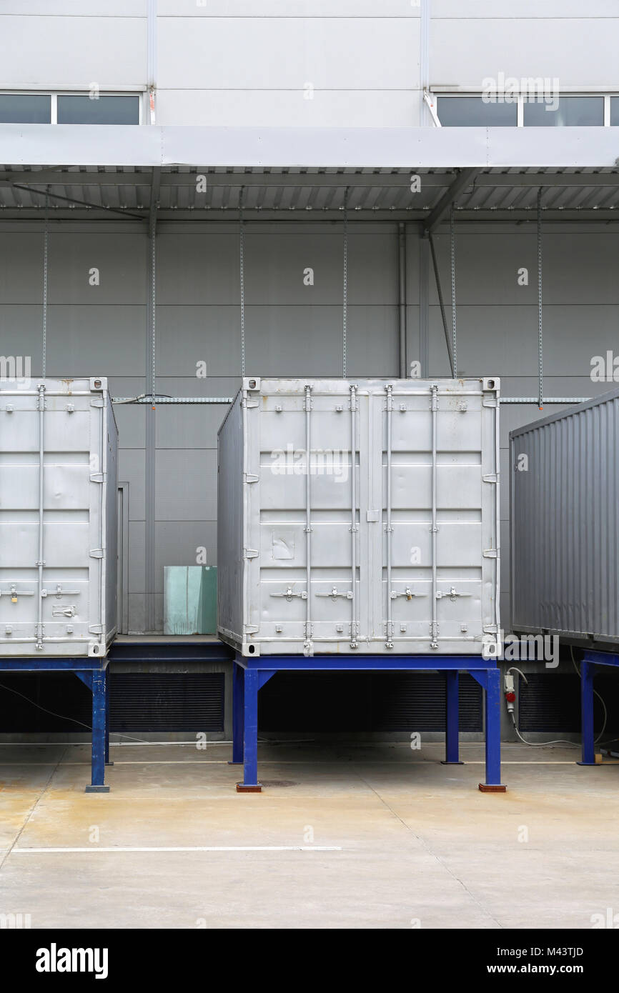 Silver Shipping Containers With Leg Support in Front of Warehouse Stock ...