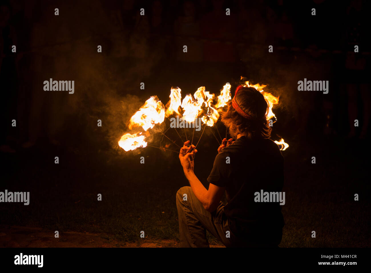 Young male performing fire juggling in front of excited crowd. Fire ...