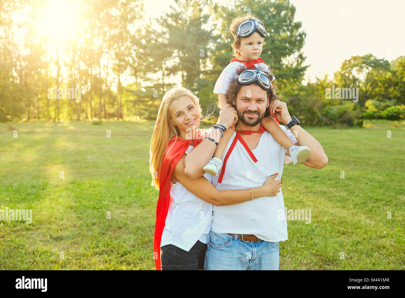 Happy family in suits of superheroes in the park Stock Photo - Alamy