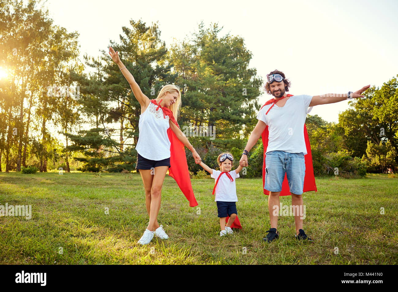 Happy family in suits of superheroes in the park Stock Photo - Alamy