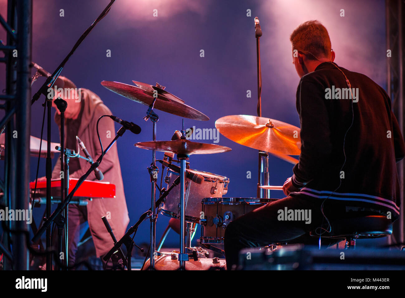 Artist playing on keyboard synthesizer piano keys, man playing drums on ...