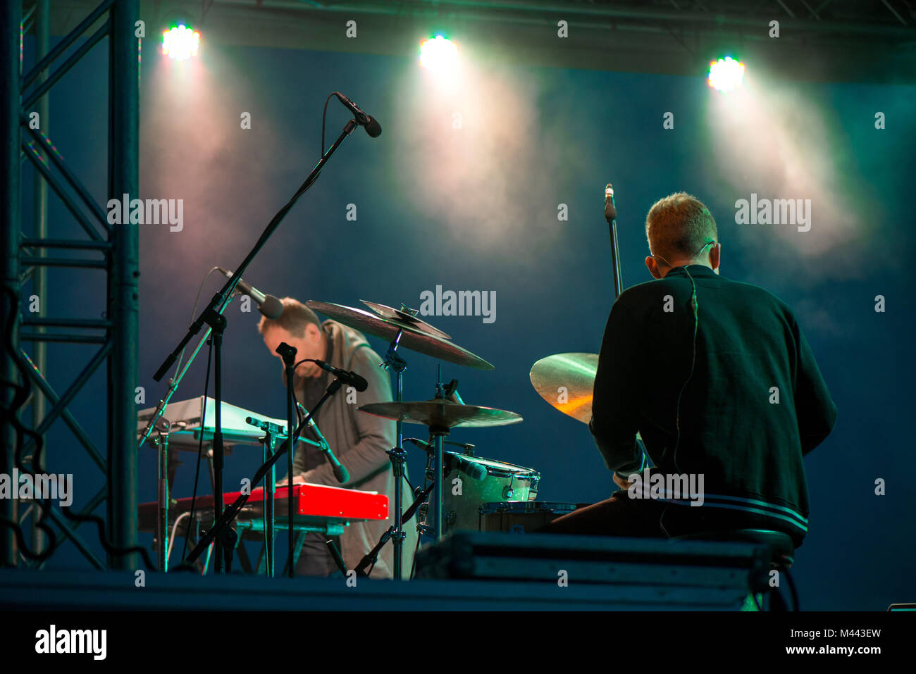 Artist playing on keyboard synthesizer piano keys, man playing drums on ...