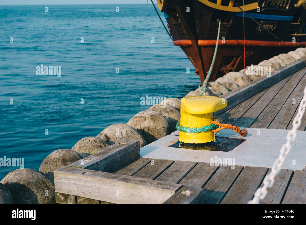 Mooring bollard on a wooden pier with a docked pirate ship in the ...
