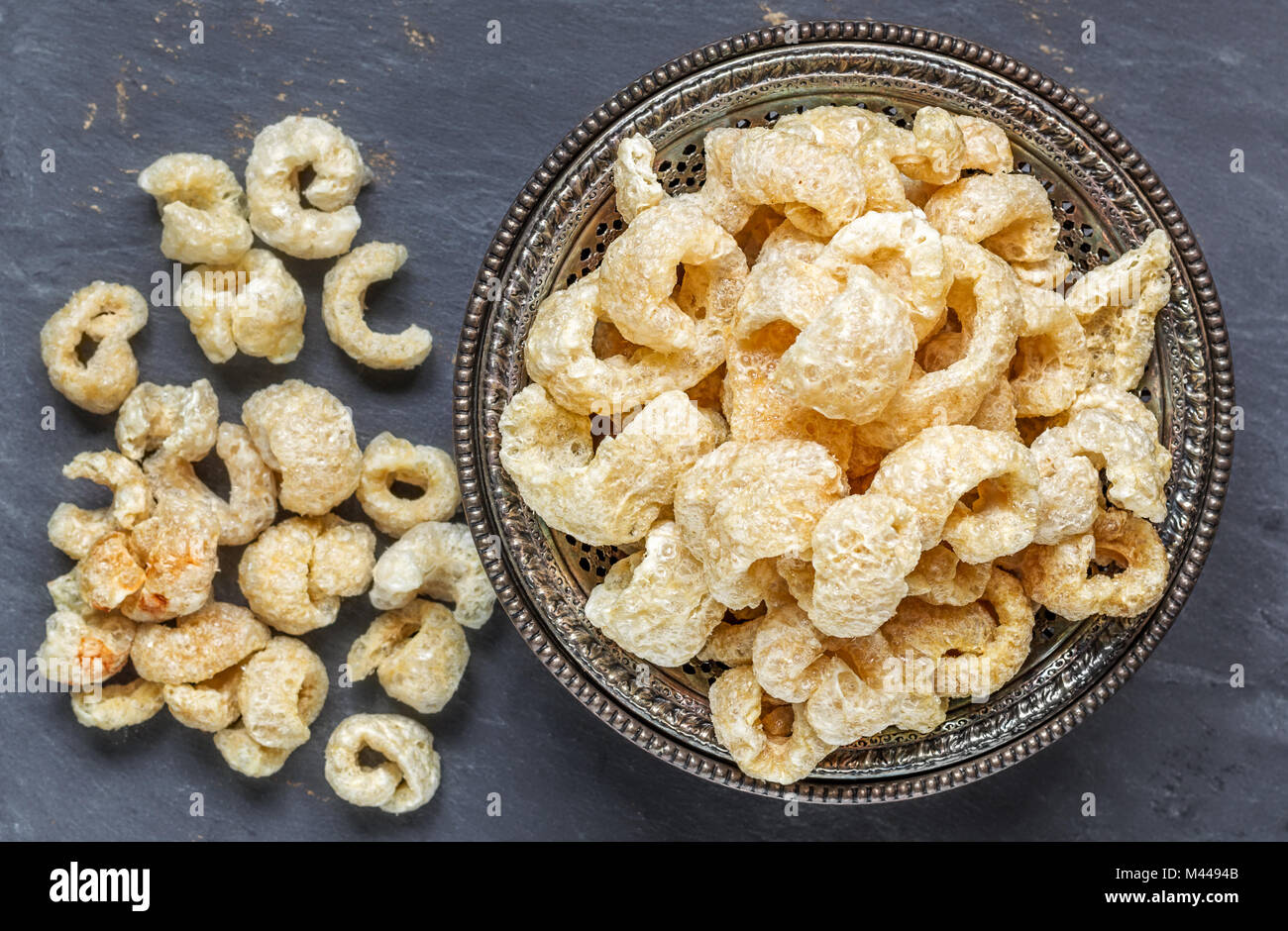 Antique metal bowl with crunchy pork cracklings with gray slate ...