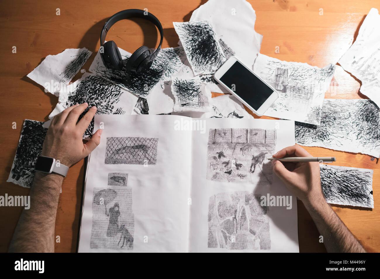 Overhead view of male artist drawing in sketchbook in artists studio ...