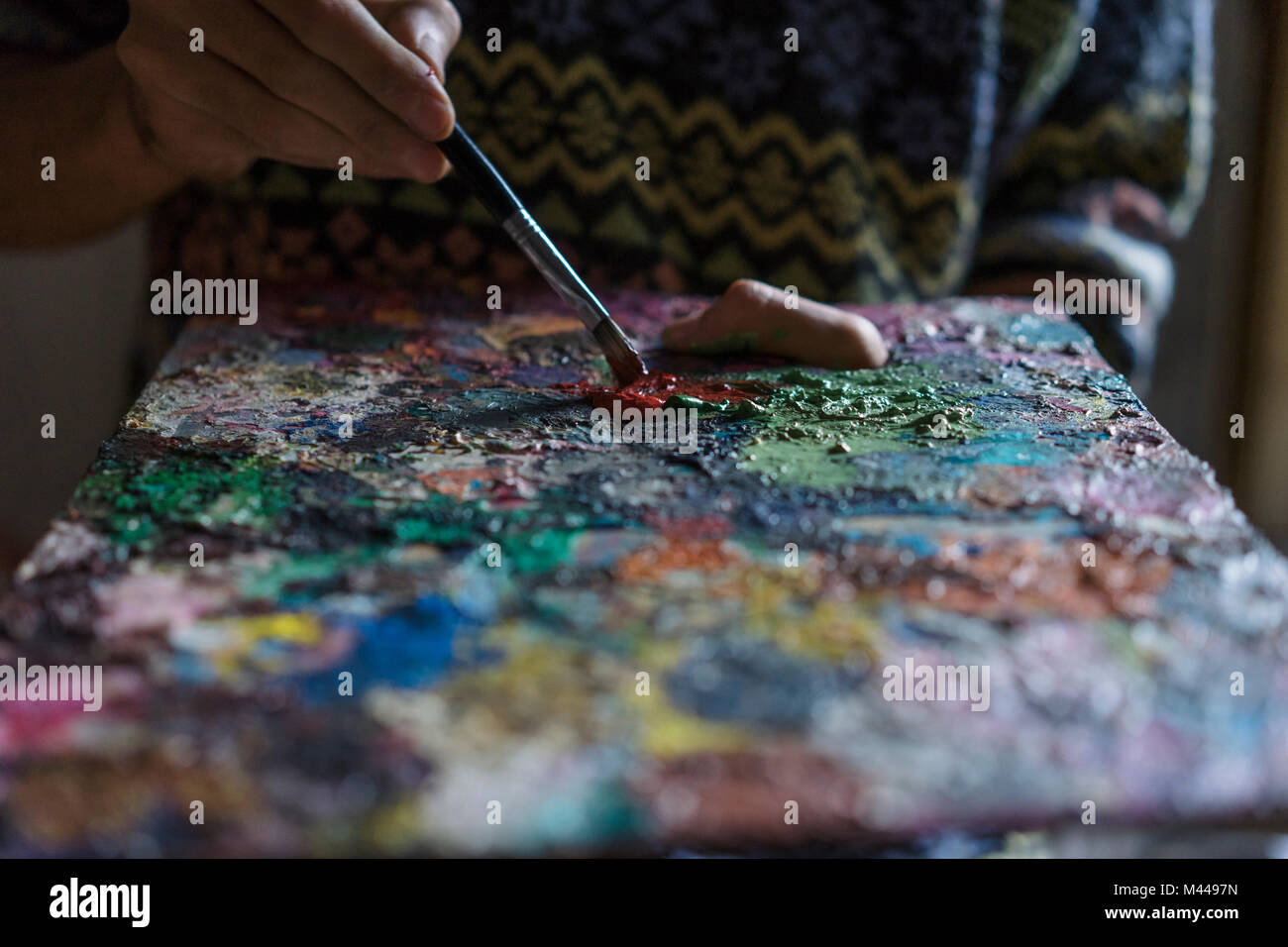 Male artist mixing oil paint on palette in artists studio, close up ...