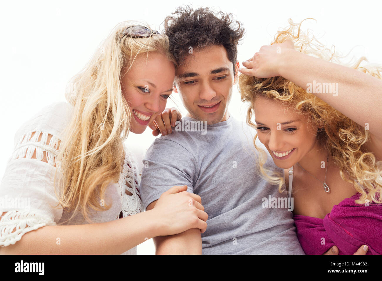 Friends huddled together smiling, looking down Stock Photo - Alamy