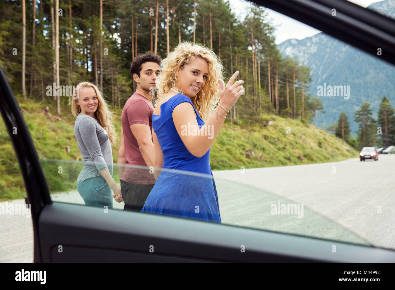 View through car window of friends looking over shoulder at camera ...