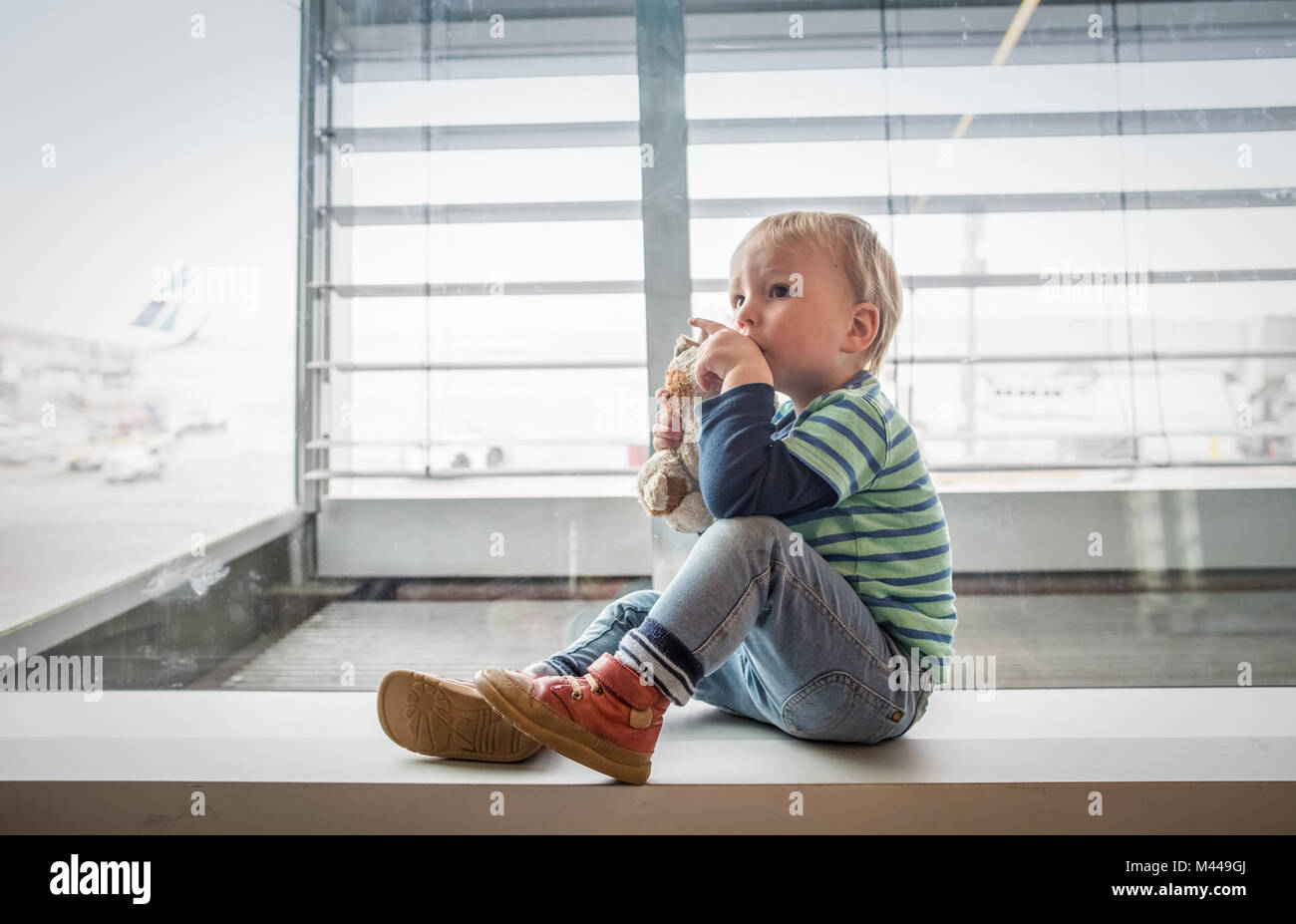 Boy sitting beside window Stock Photo - Alamy